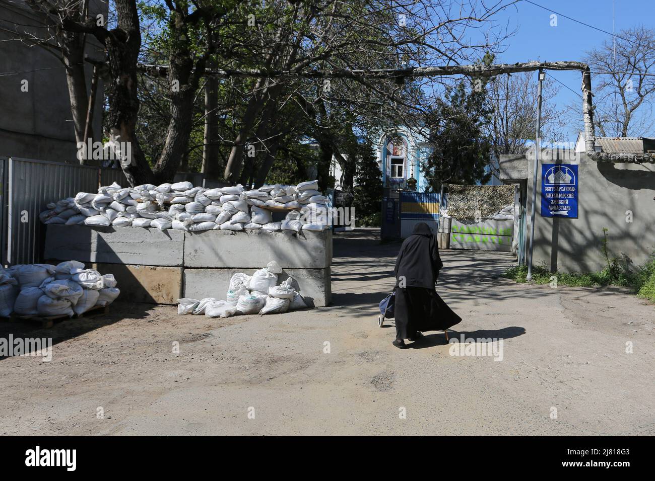 An elderly nun in a black cassock with a stick and a wheelbarrow in her ...