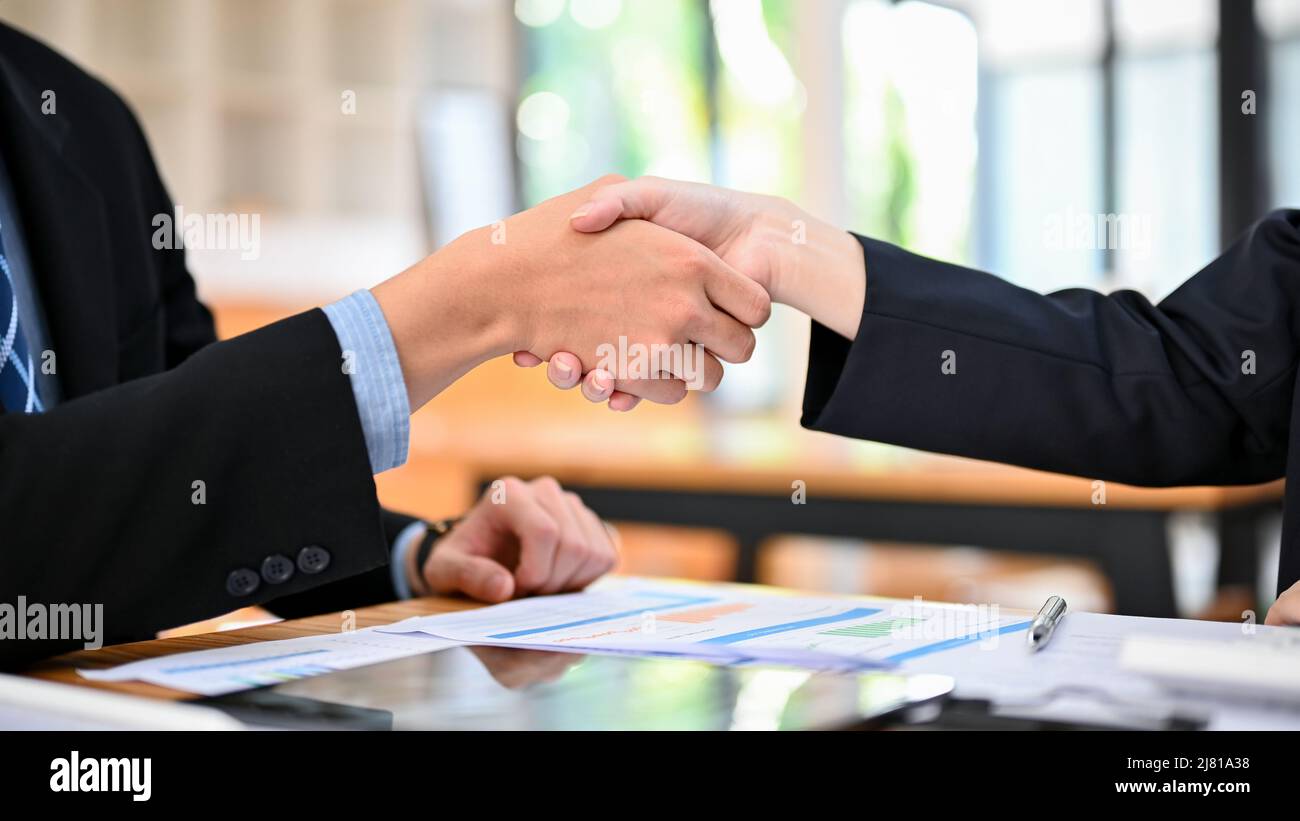 Two business people in the formal suit shaking hands in the meeting ...