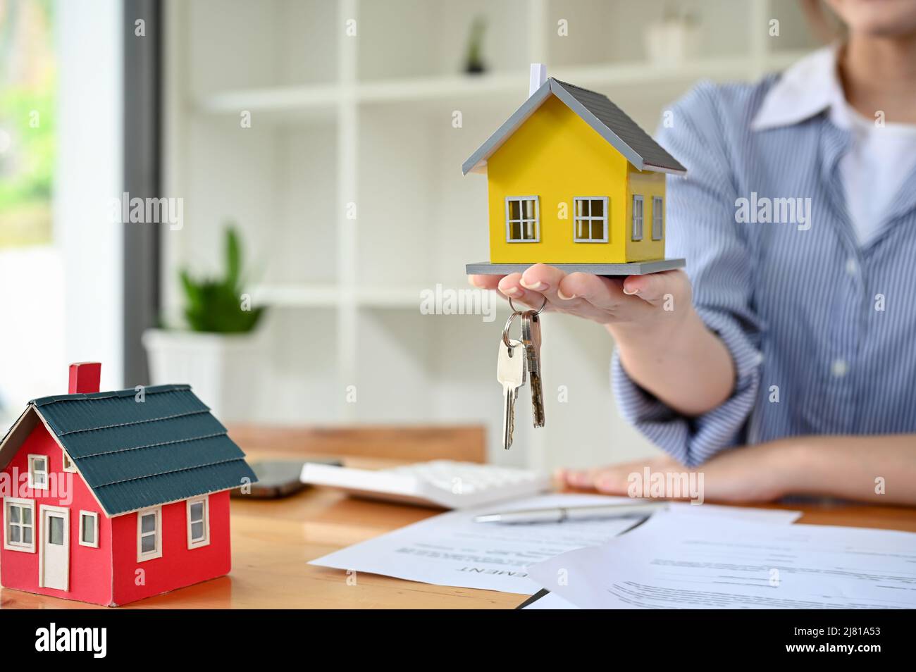 Female real estate agent holding or showing a house model and house ...