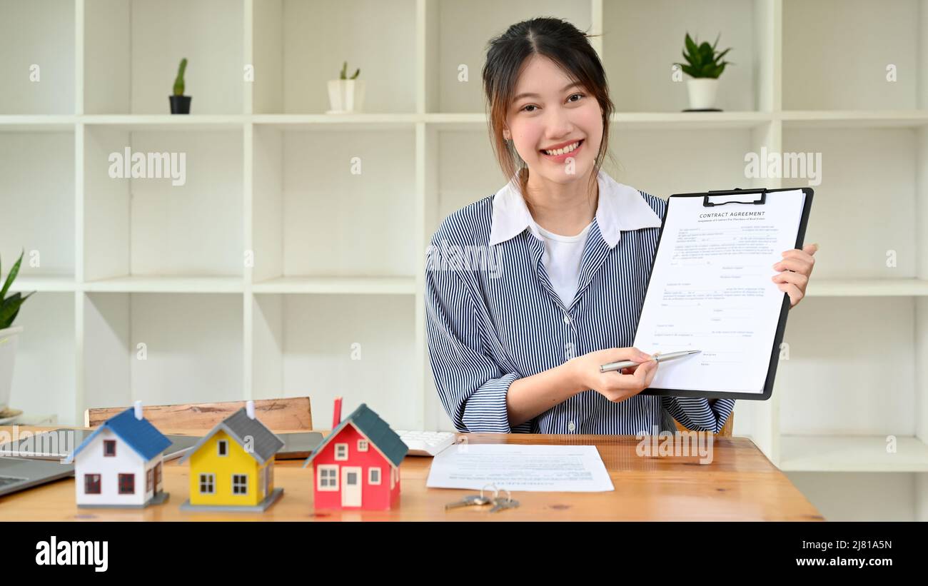 Beautiful and charming Asian young female real estate agent showing a ...