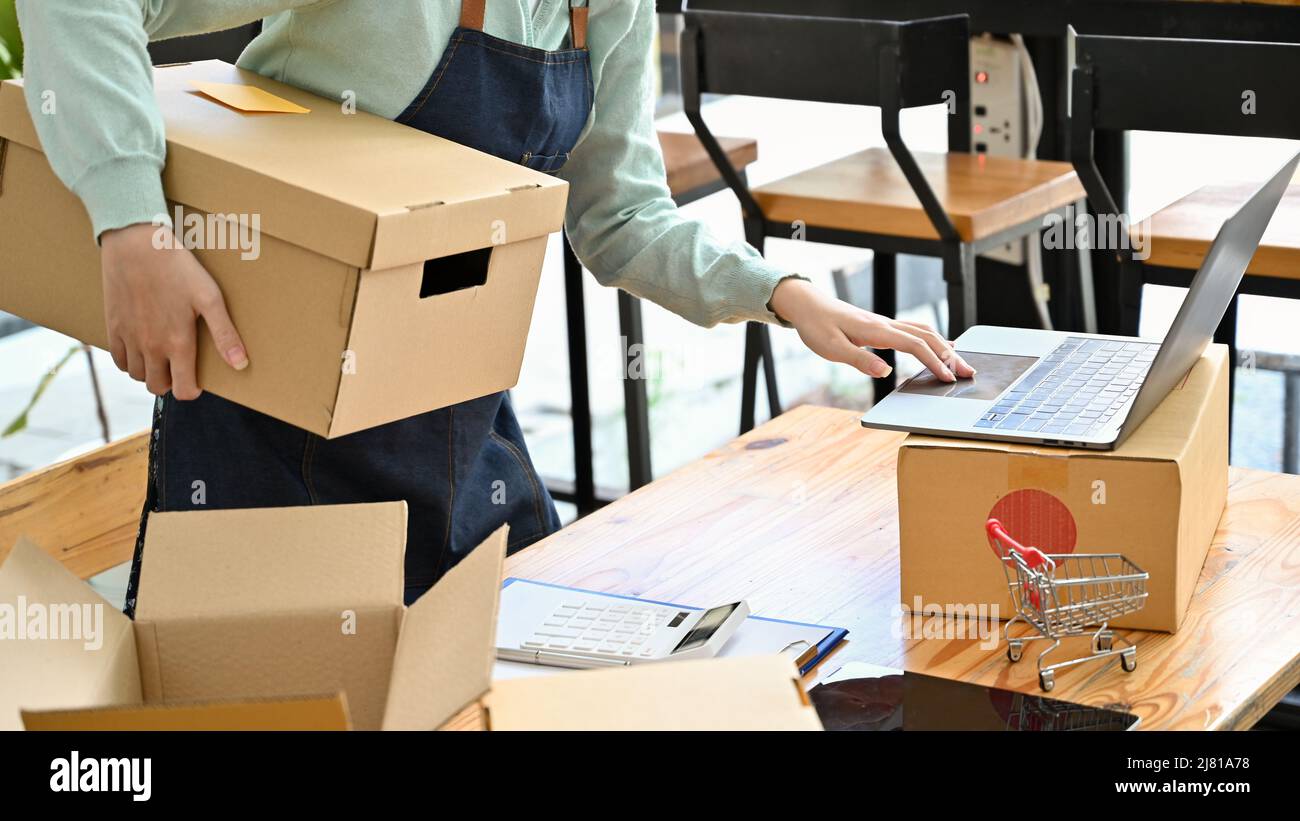 Female worker using laptop computer and packing the delivery boxes in ...