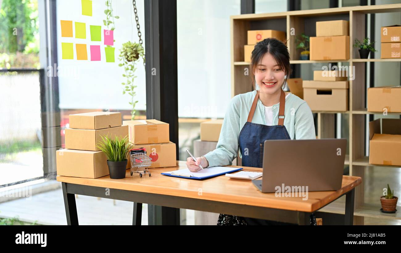 Attractive Asian young female e-commerce business owner using laptop ...