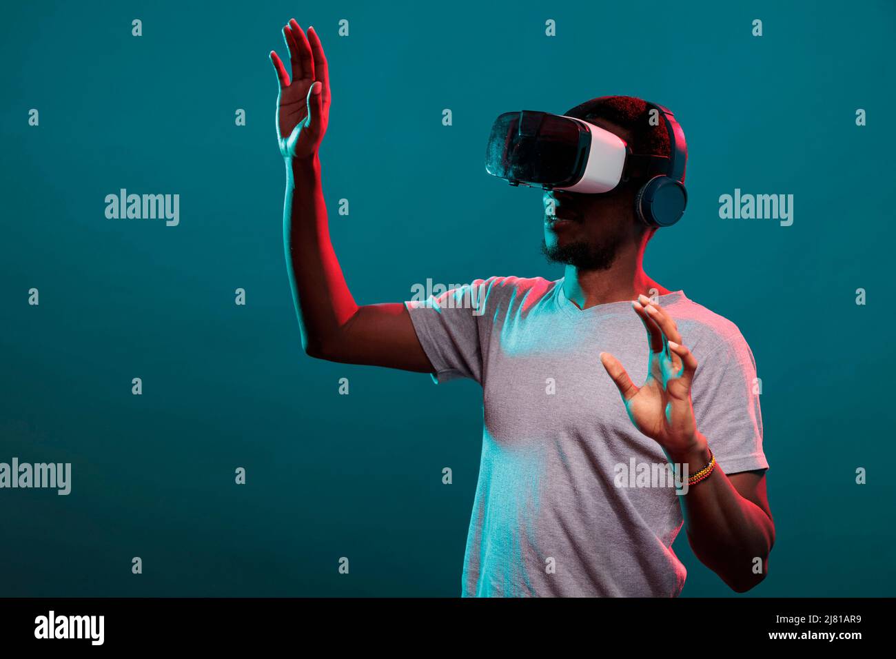 Young adult raising hands to play futuristic game with vr goggles ...