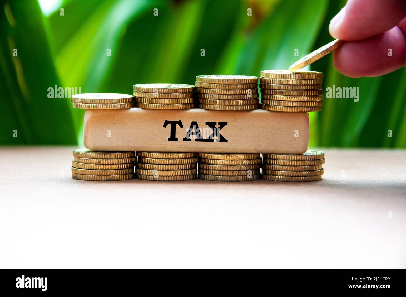 Tax text on wooden block with stack of gold coins on blurred background ...