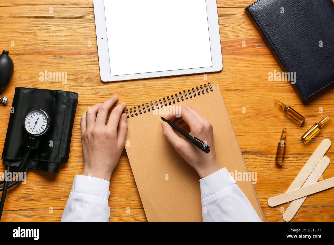 Female doctor writing in notebook on wooden background Stock Photo - Alamy