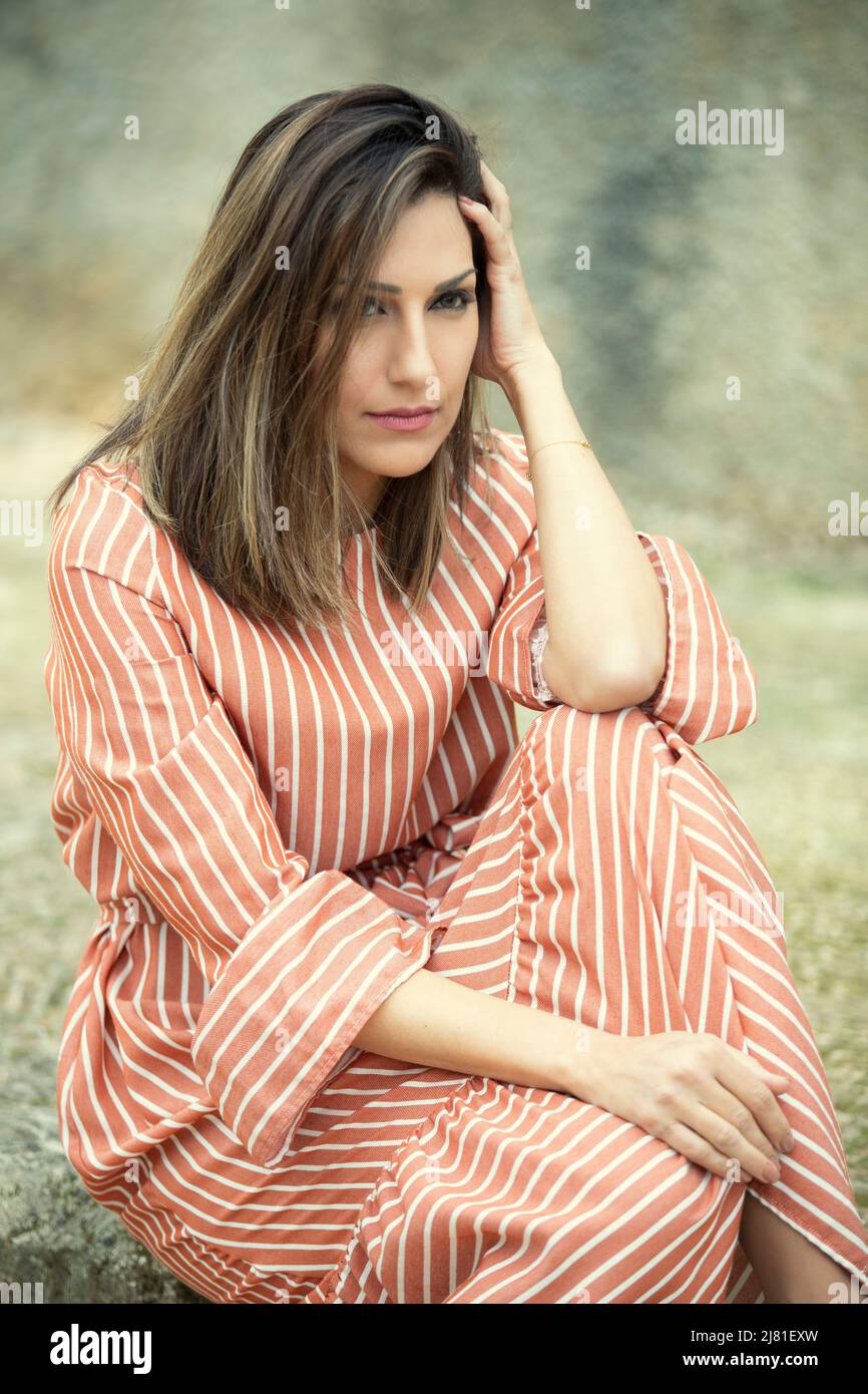 Beautiful serious woman sitting on the pavement looking away Stock ...