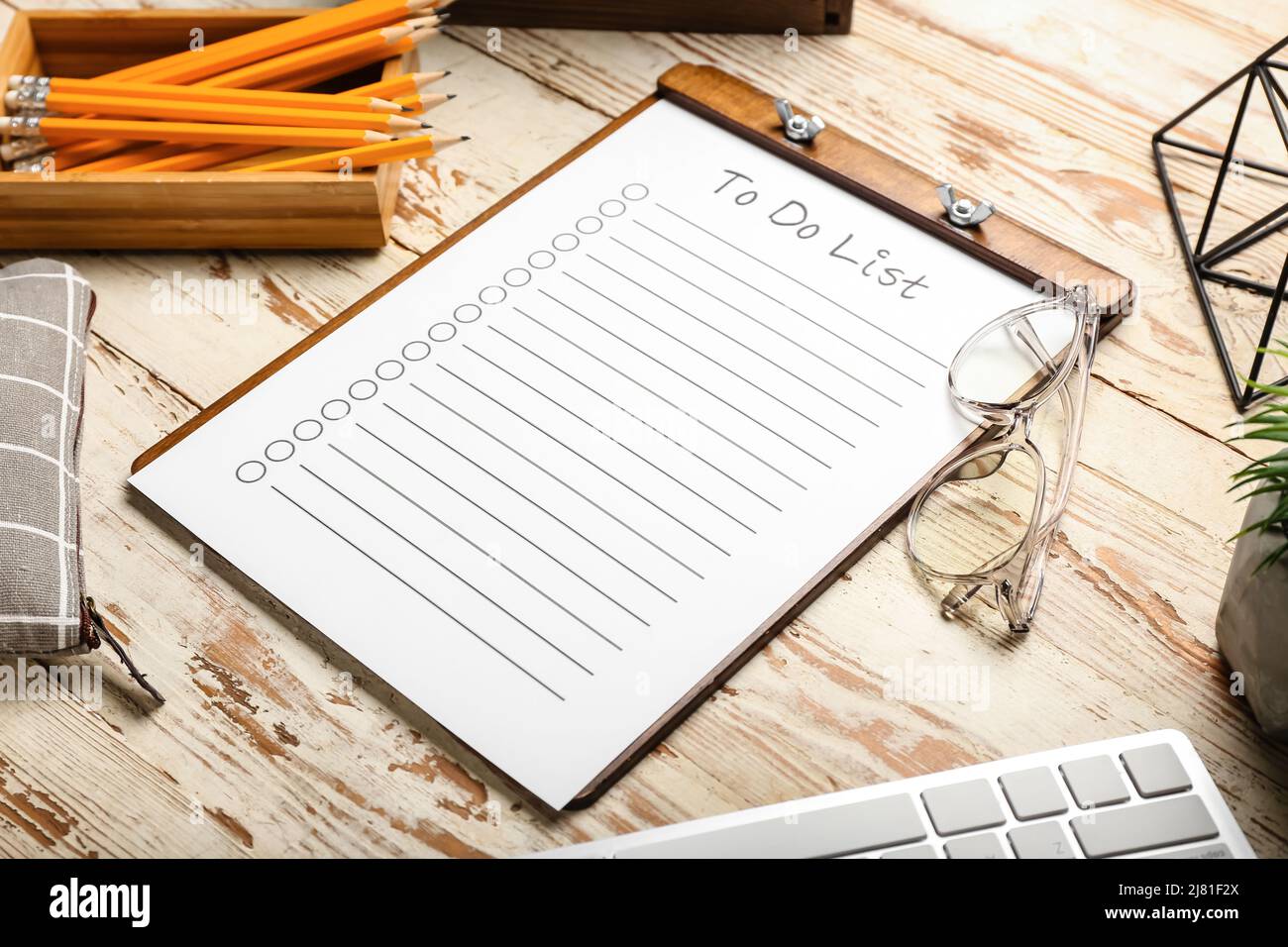 Clipboard with blank to do list, eyeglasses and pencils on light wooden ...