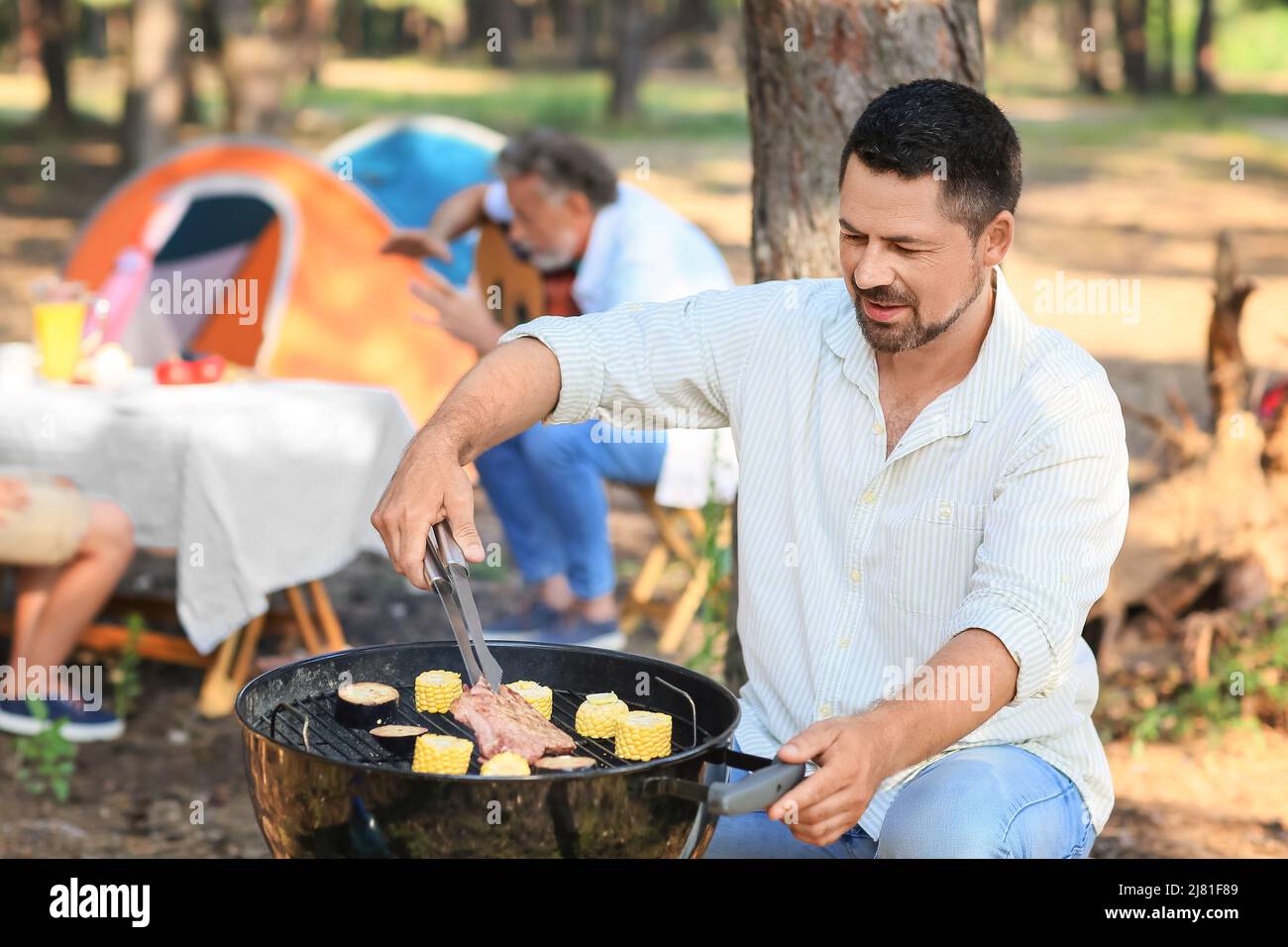 Handsome man cooking food on grill at barbecue party Stock Photo - Alamy