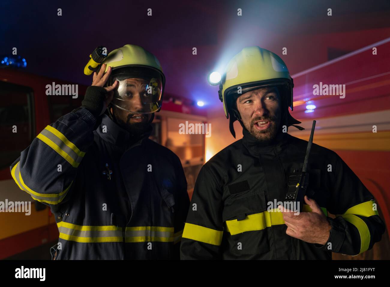 Firefighters men at action with fire truck in background at night Stock ...