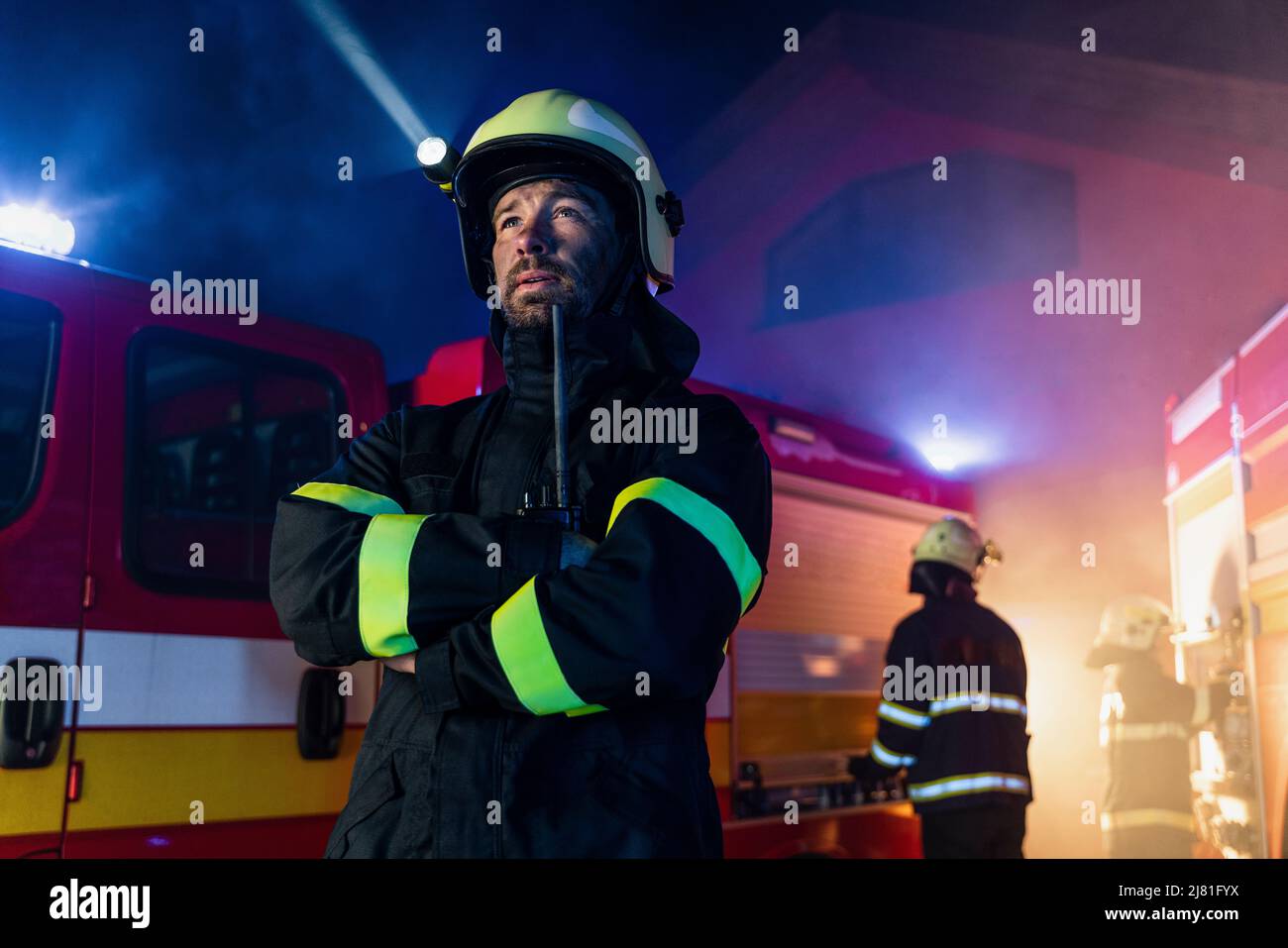Low angle view of firefighter with fire truck in background at night ...