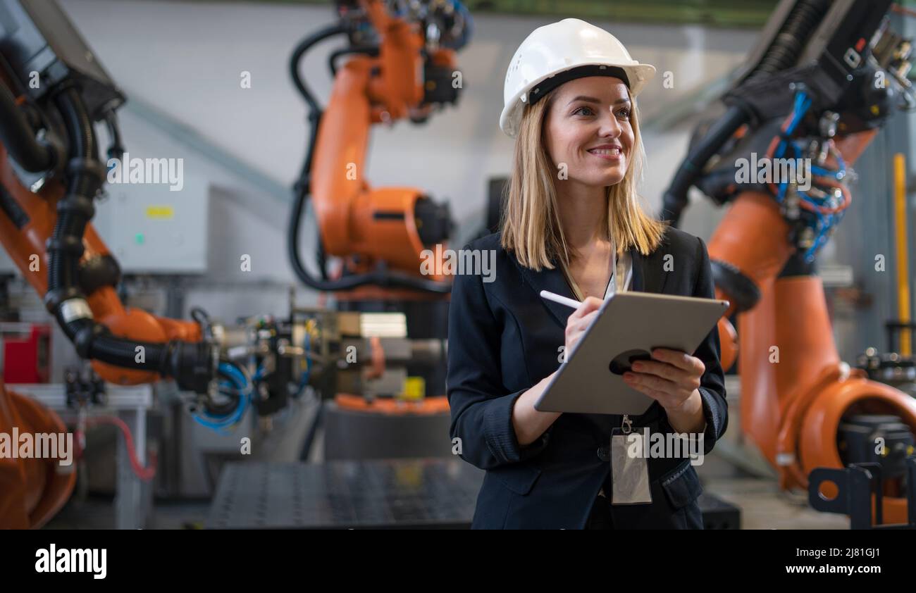 Female chief engineer in modern industrial factory using tablet and ...
