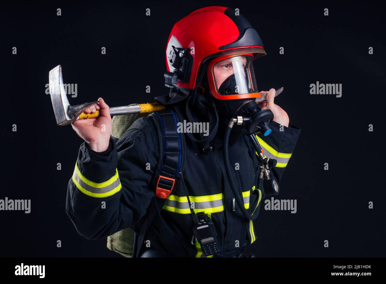 portrait strong fireman in fireproof uniform holding an ax in his hands ...
