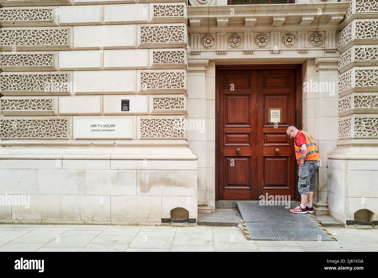 A Royal Mail postman at a door of the british civil service Treasury ...