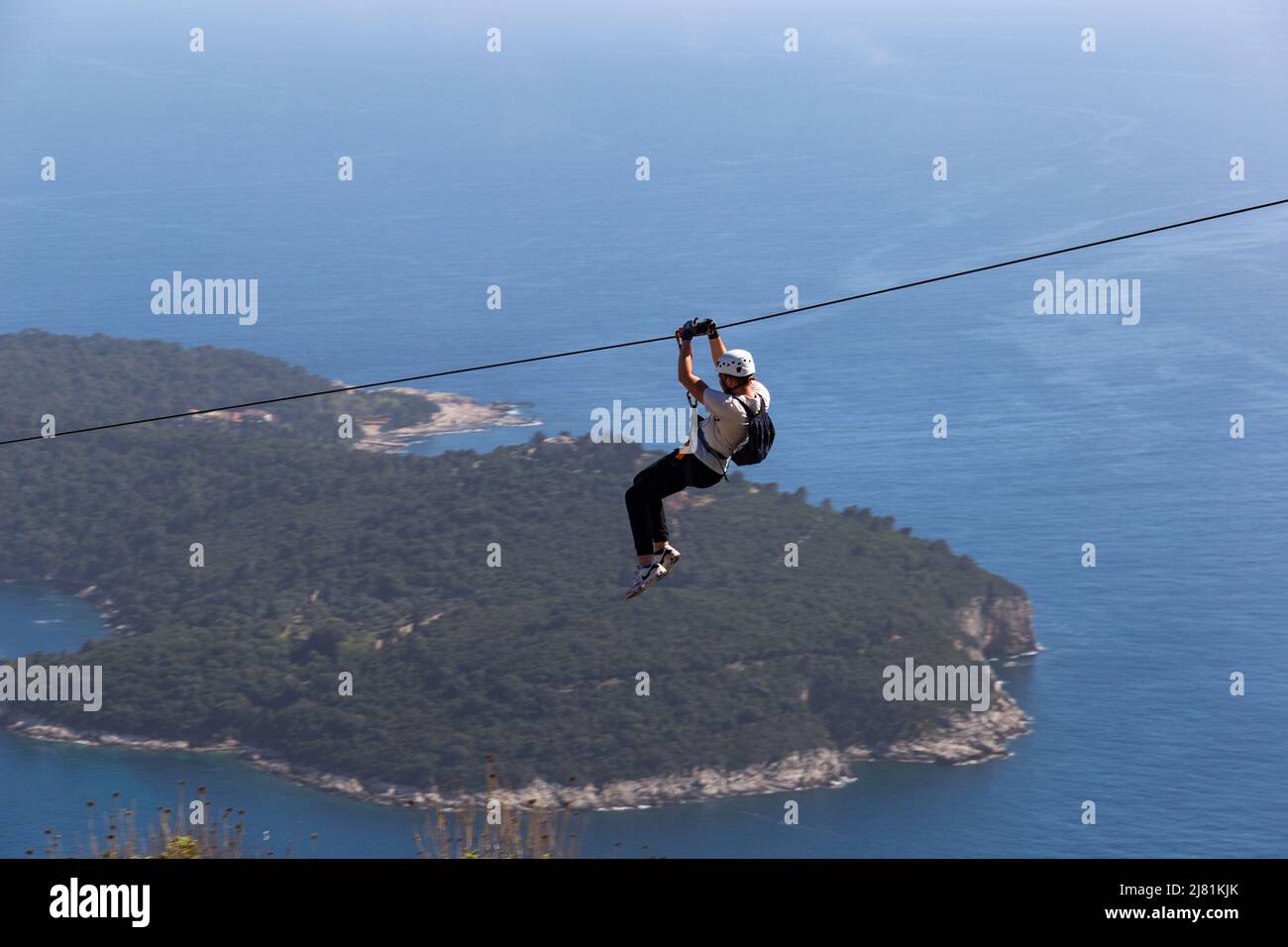Man going down on rope above Adriatic sea. Adventure attraction near ...