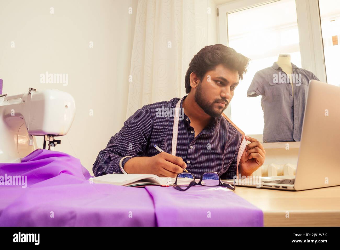 tailor asian man designer sewing clothes on sewing machine next to ...