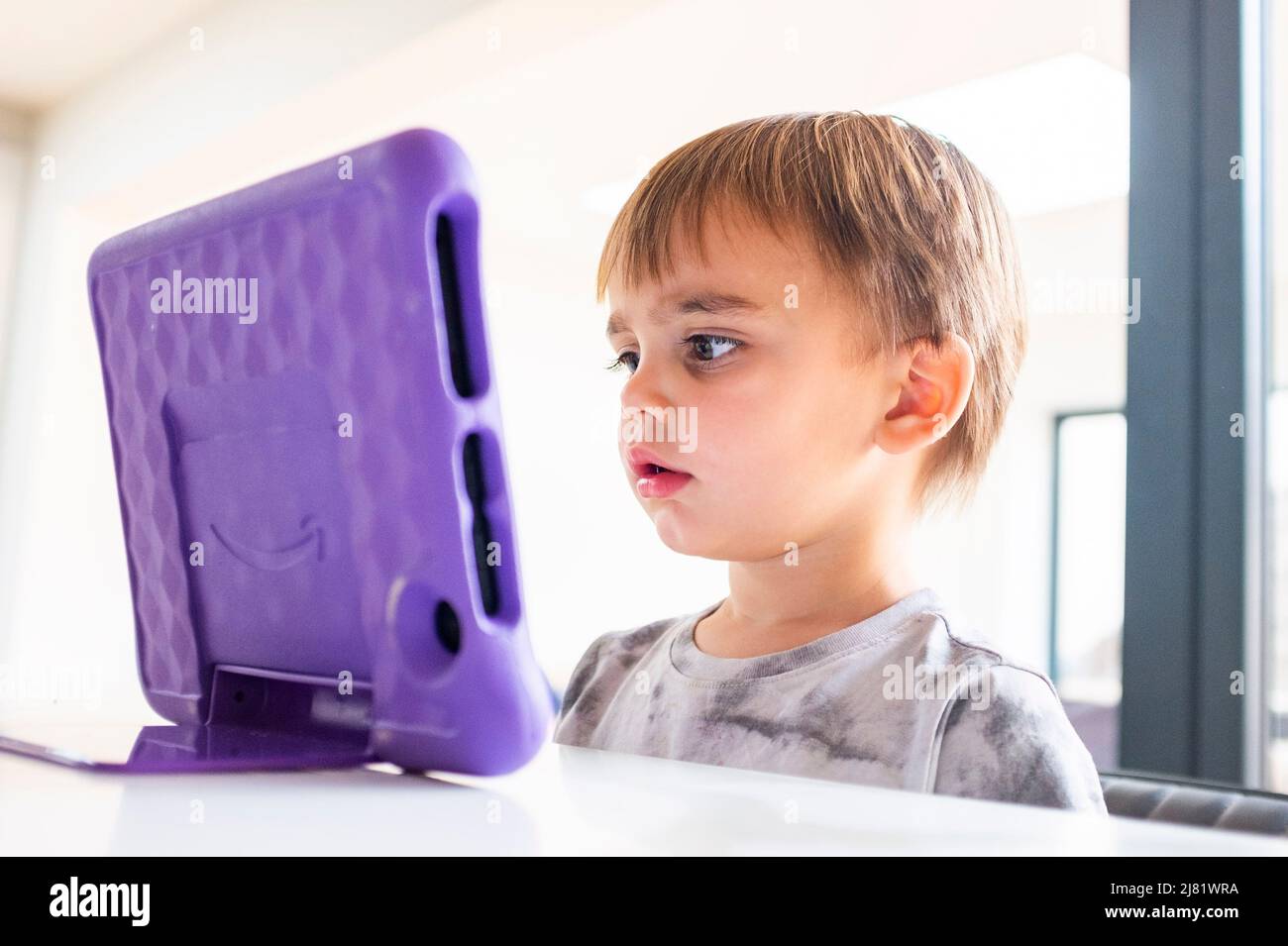 Young infant boy of two and a half years old concentrating as he uses a ...