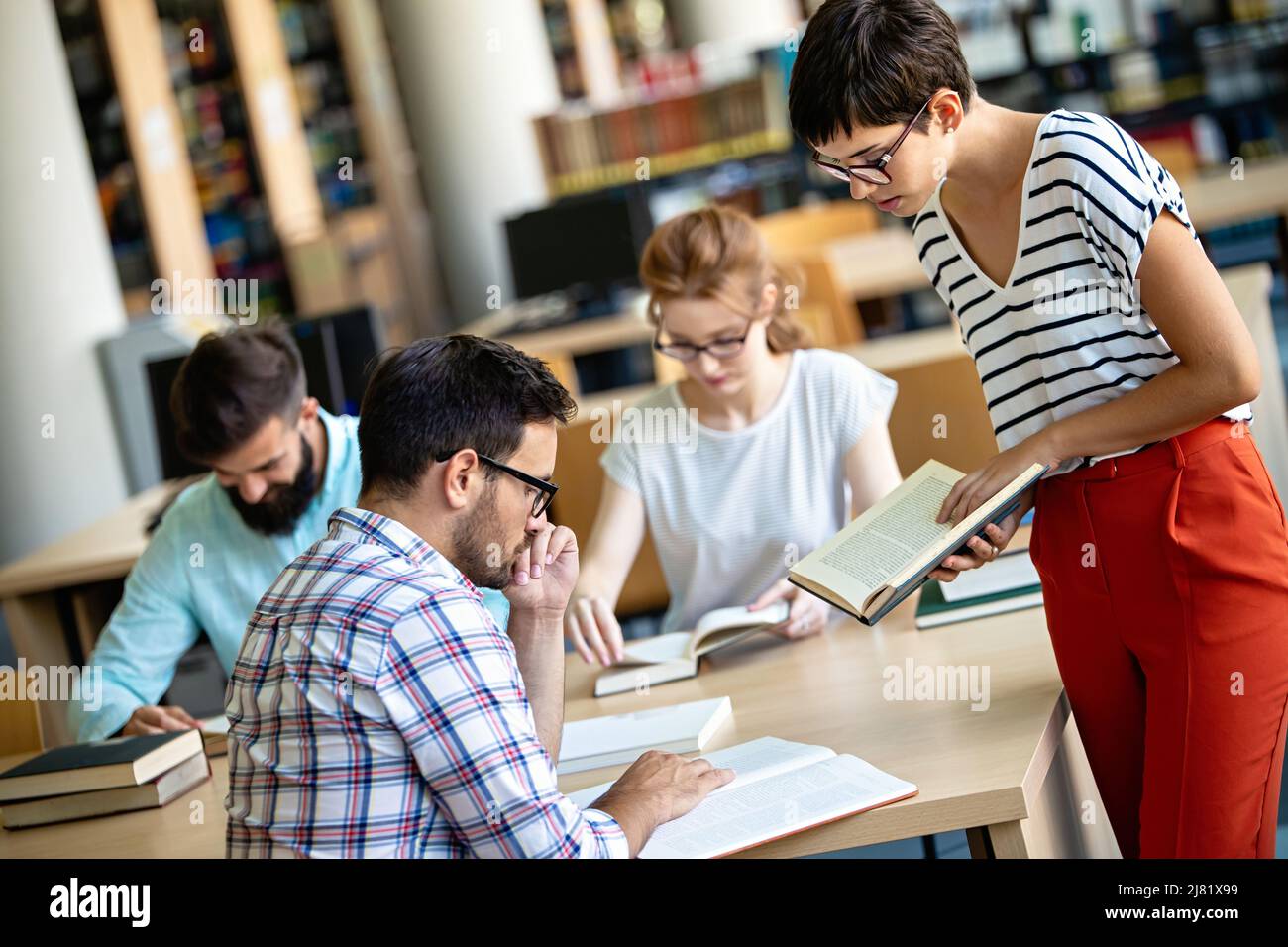 Happy university students studying with books in library. Group of ...