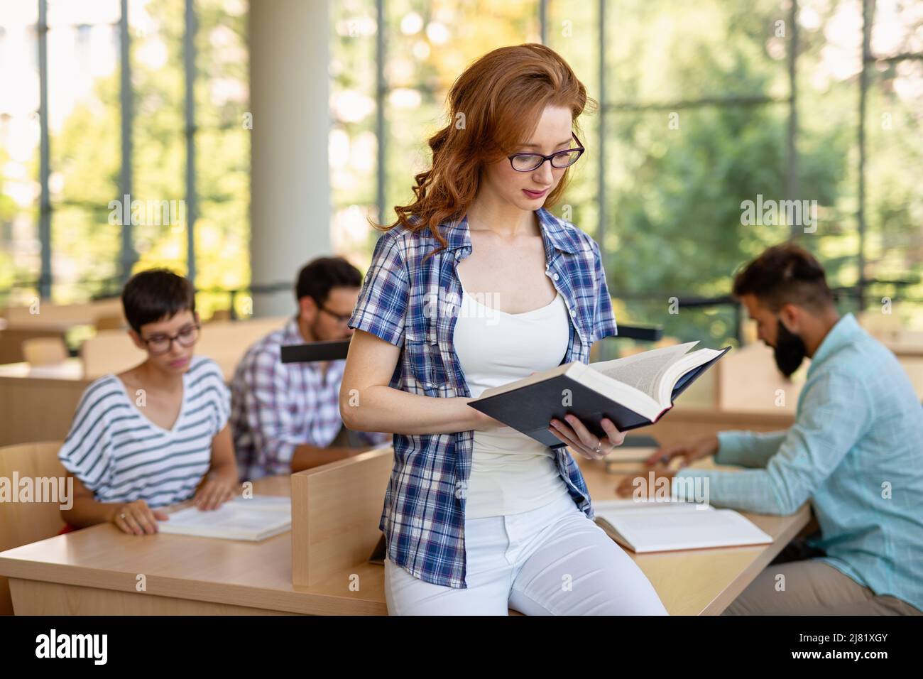 Happy university students studying with books in library. Group of ...