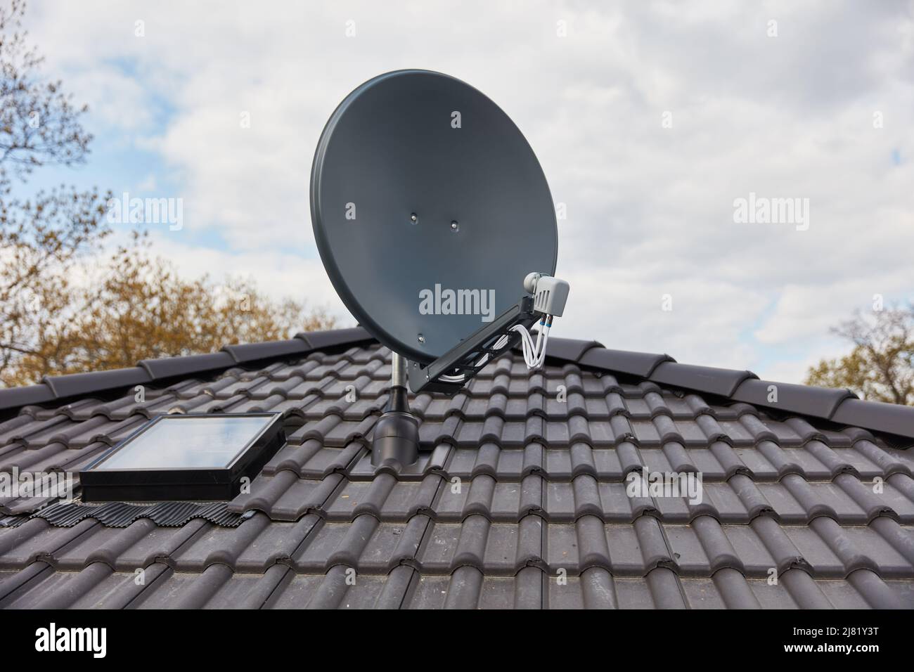 Satellite dish on the roof of the house next to the skylight for ...