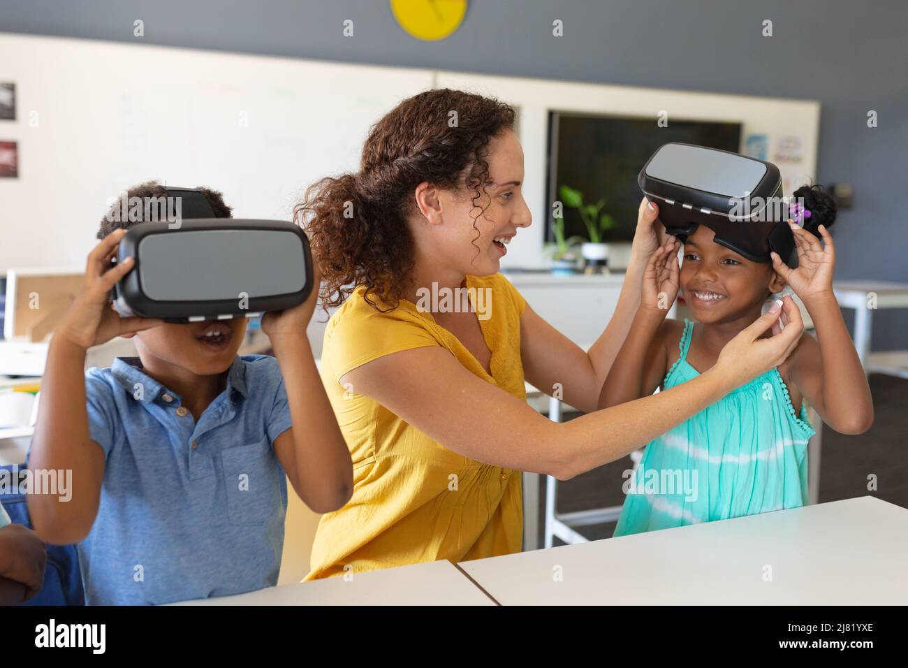 Caucasian young female teacher wearing vr glasses to african american ...