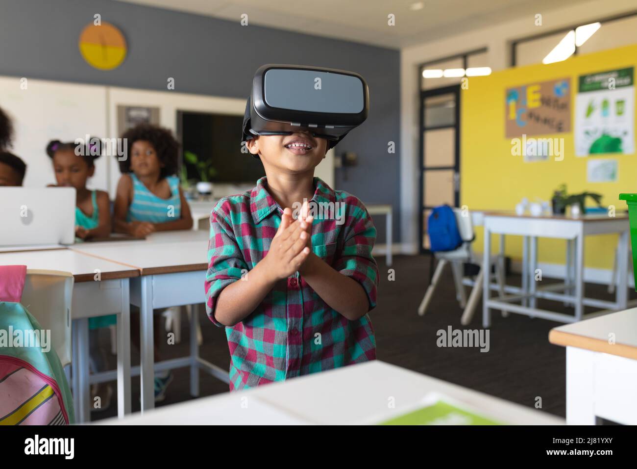 Smiling african american elementary schoolboy wearing vr glasses while ...