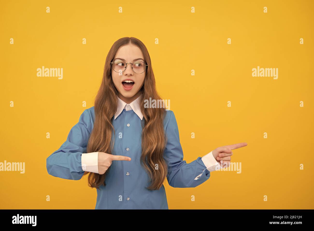 Surprised kid point fingers yellow background. Pointing for advertising ...