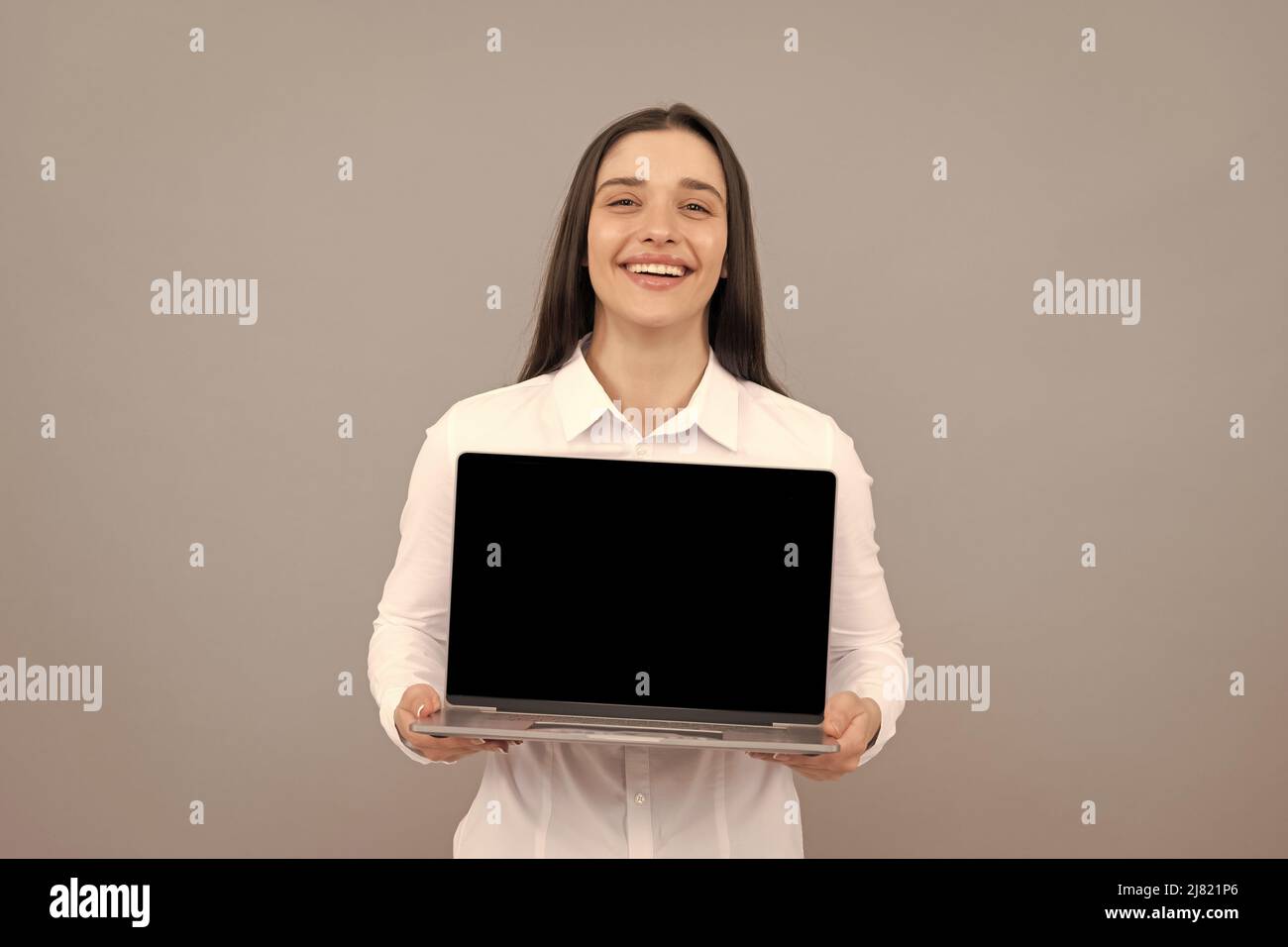 happy woman in white shirt showing computer ad presentation, copy space ...