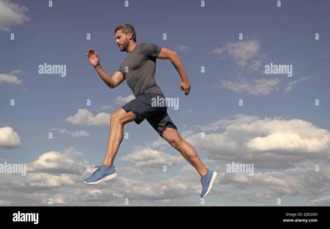 sportsman with muscular body running in sportswear outdoor on sky ...
