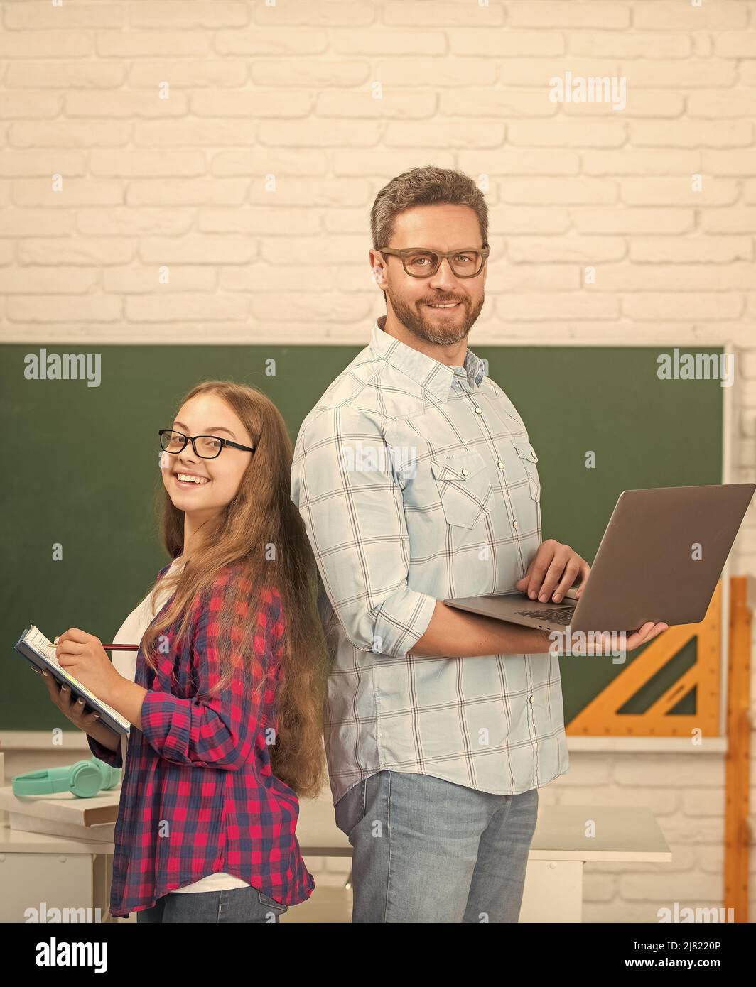 happy kid and dad in classroom with copybook and computer at blackboard ...