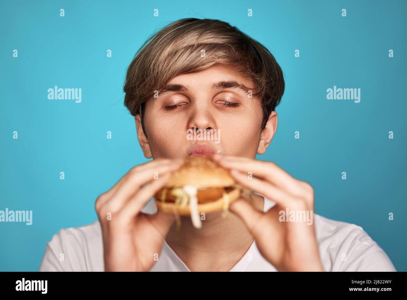 Very hungry young man holding tasty hamburger Stock Photo - Alamy