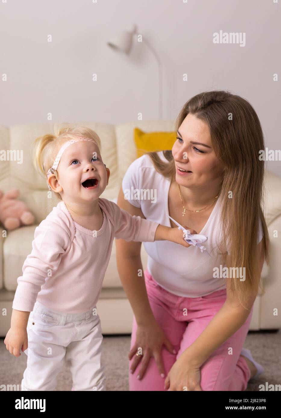 Cochlear implant on the child girl head and playing with mother Hearing ...