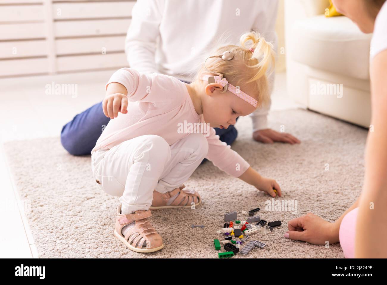 Cochlear implant for baby. Deaf child with hearing aid plays in living ...