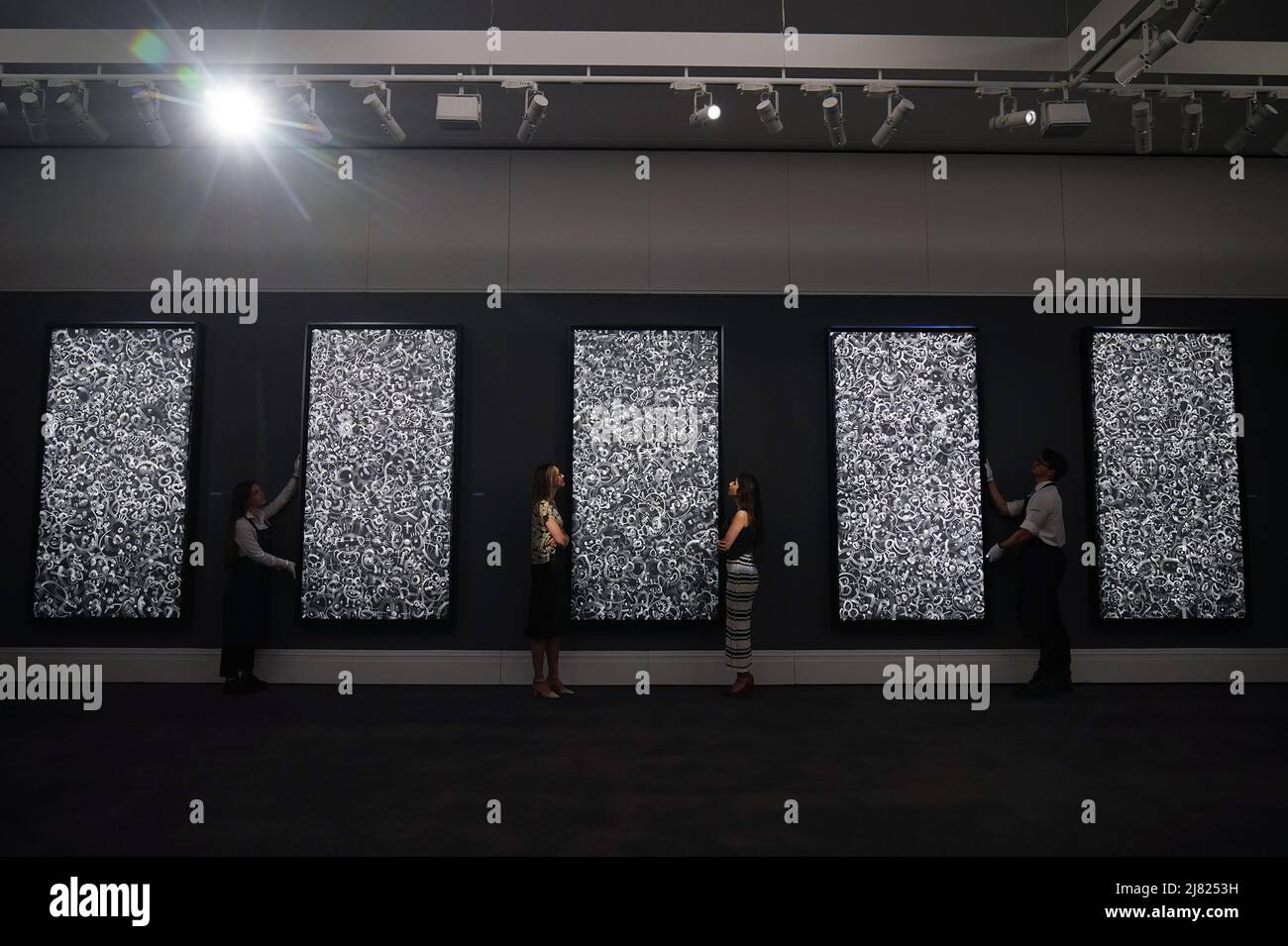 Art handlers and staff pose next to work on display at Sotheby's in ...