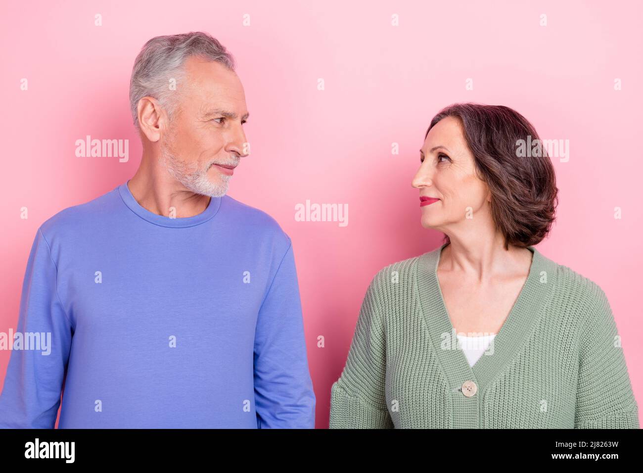 Portrait of two calm peaceful people look each other isolated on pink ...