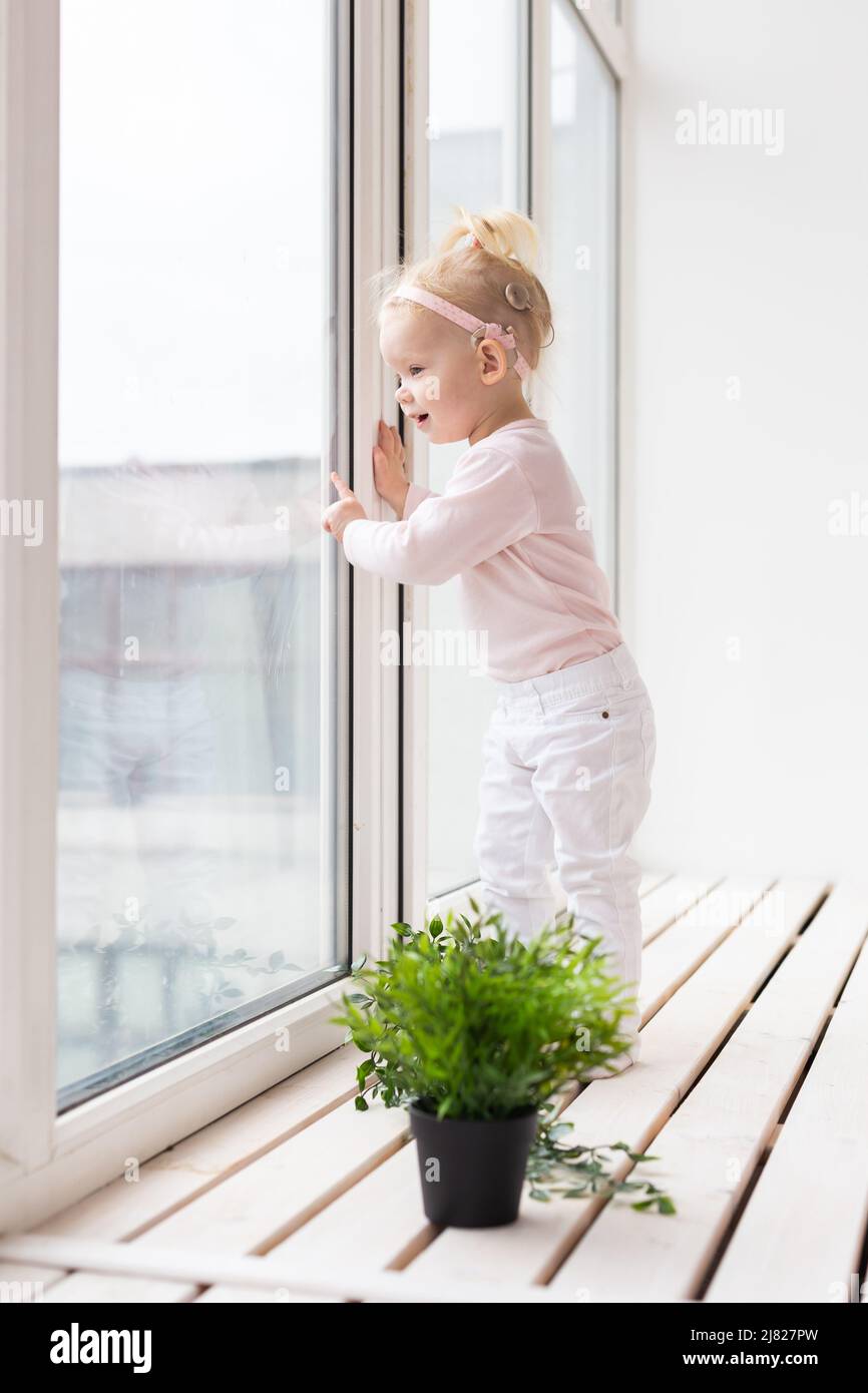 Cochlear implant for baby. Deaf child with hearing aid plays in living ...