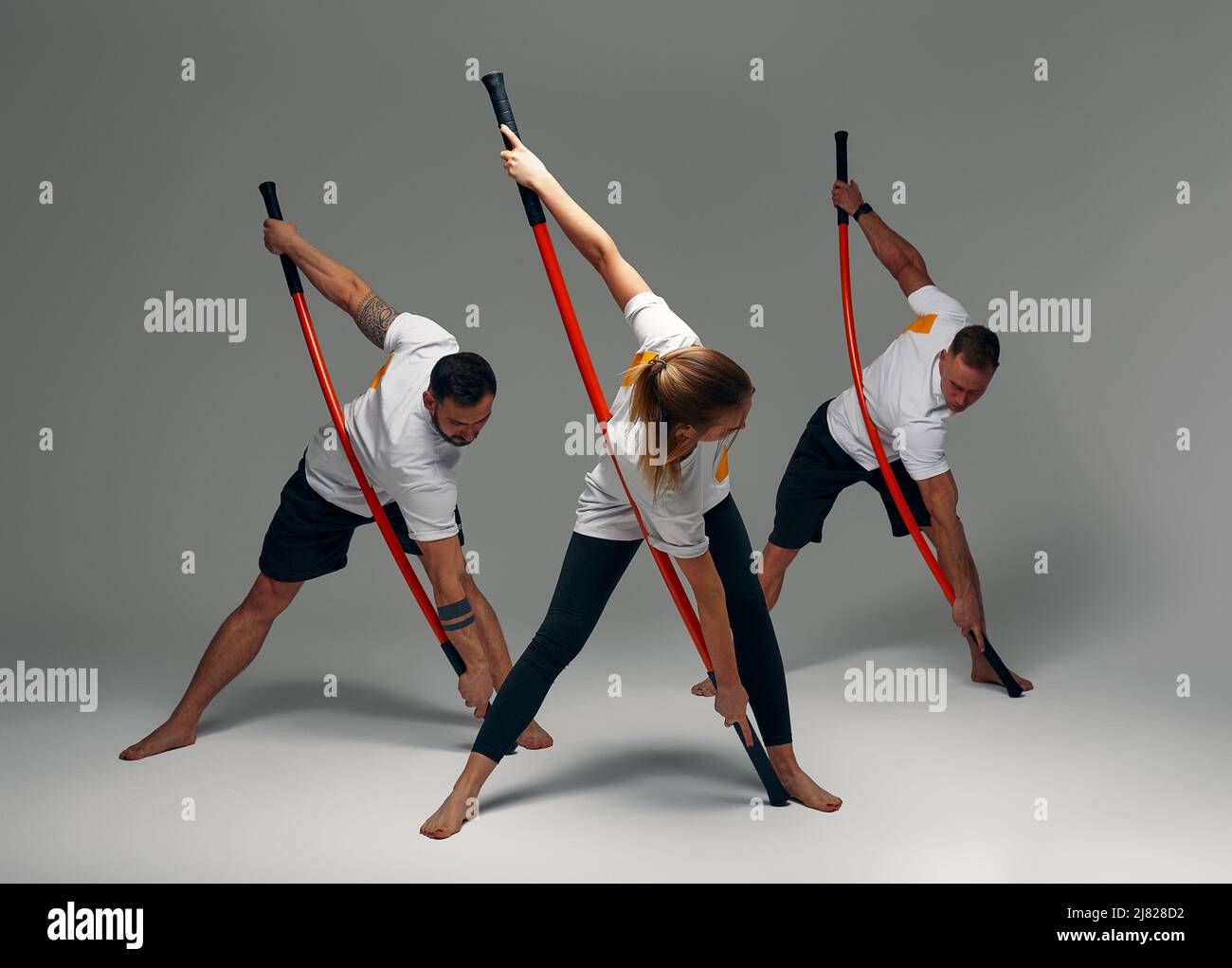 Two men and woman aikido fighters with wooden fight stick posing in ...