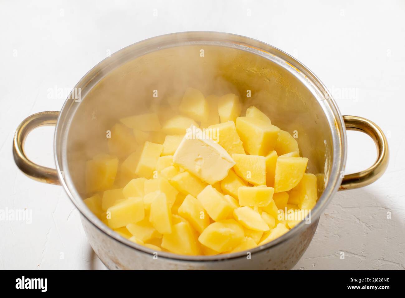 Boiled potatoes in a pot. Hot potato cubes with a piece of butter ...