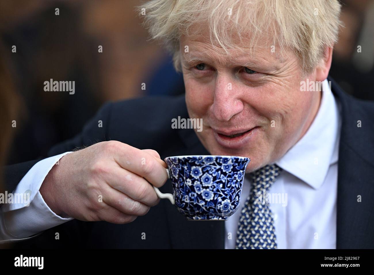 Prime Minister Boris Johnson drinks from a cup as he talks to local ...