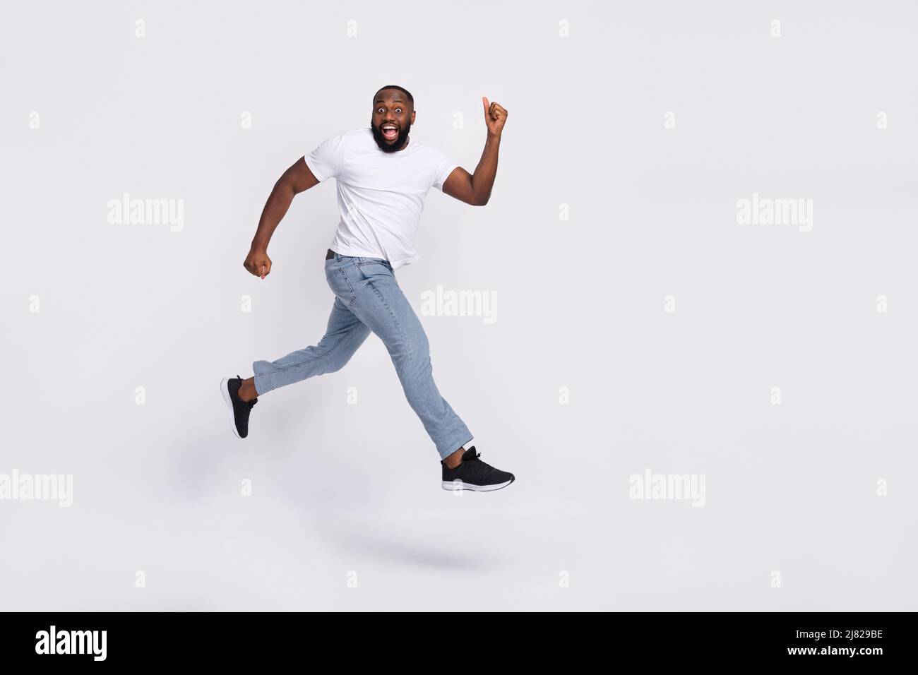 Photo of excited pretty guy dressed casual t-shirt jumping high running ...