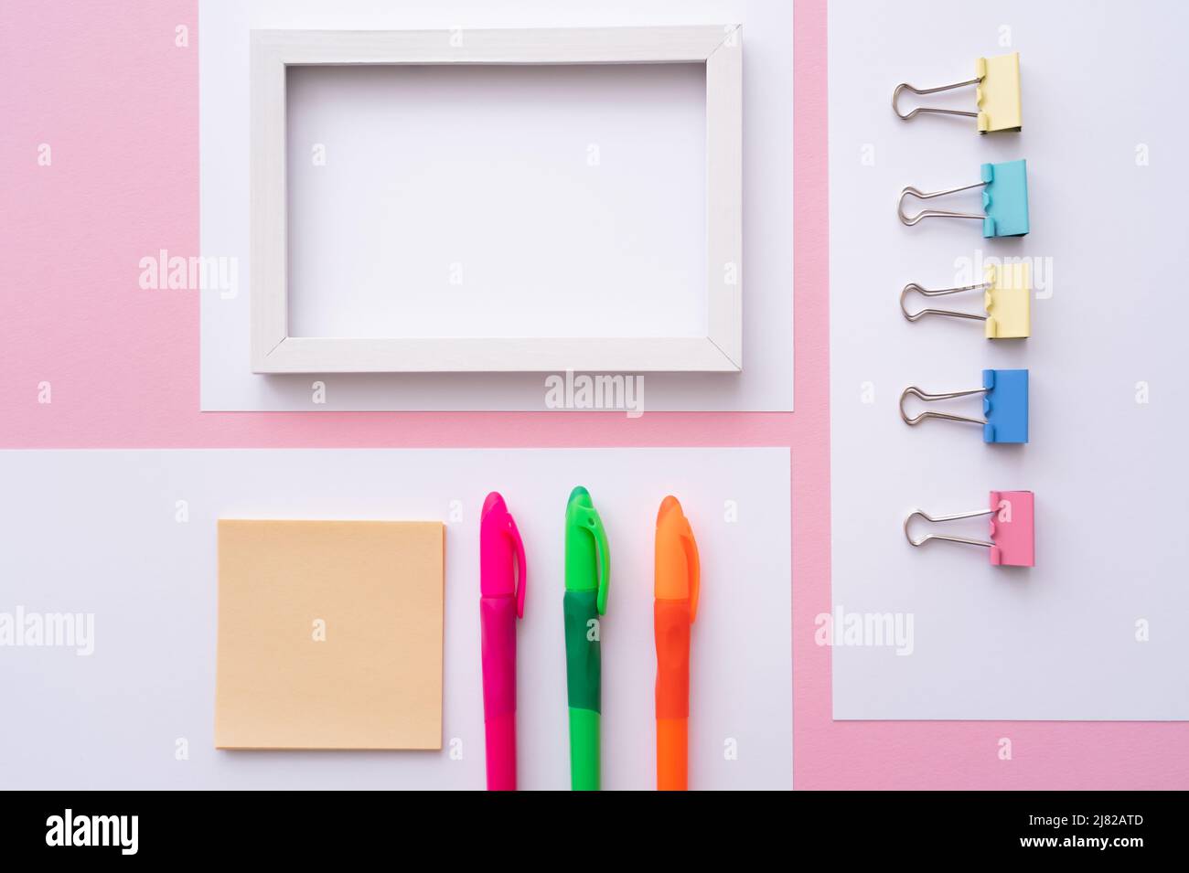 flat lay of colorful stationery near blank frame and papers on pink ...