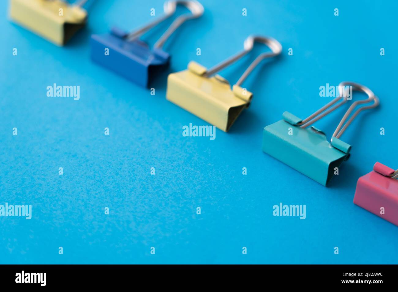 flat lay of colorful pastel fold back clips on blue Stock Photo - Alamy