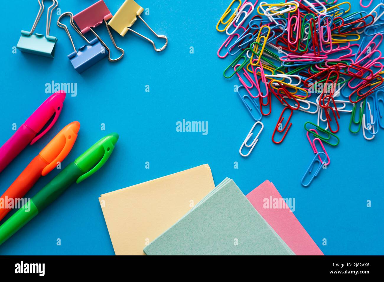 top view of colorful paper clips and fold back clips near paper notes ...