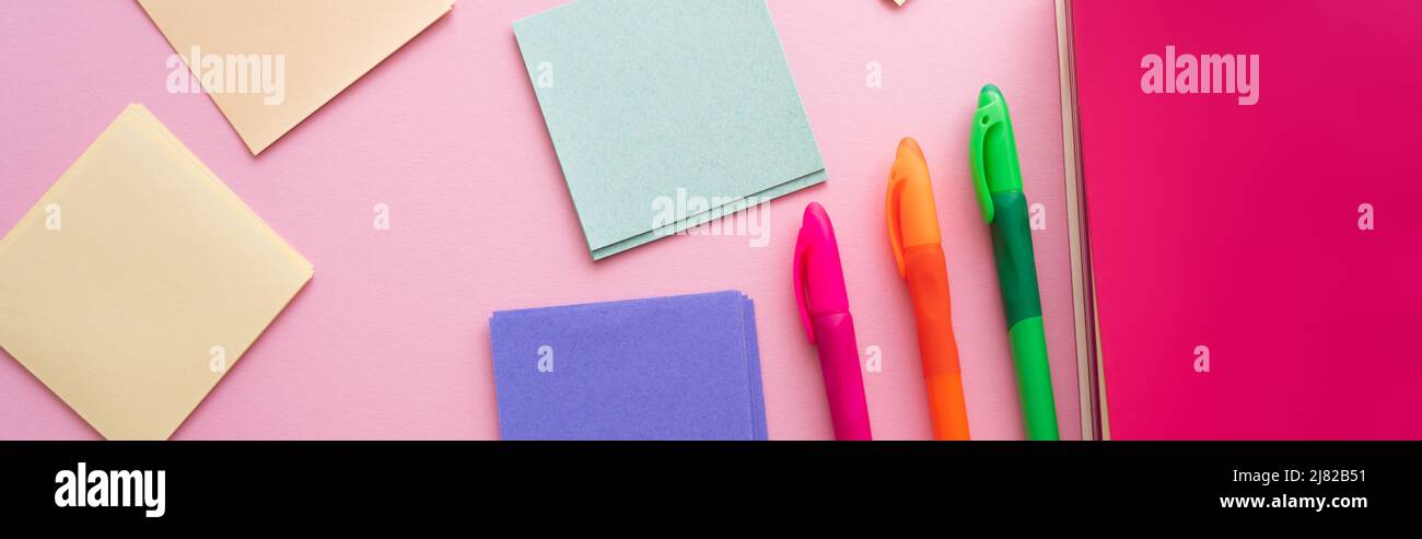 top view of colorful pens near bright notebook and blank paper notes on ...