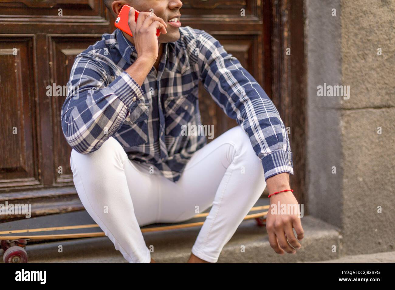 portrait anonymous black man talking on the phone sitting with a door ...