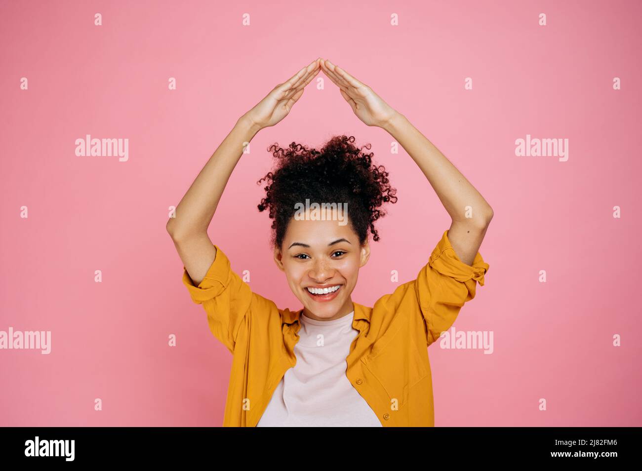 Happy Curly Haired African American Girl Making Roof Of Hands Above