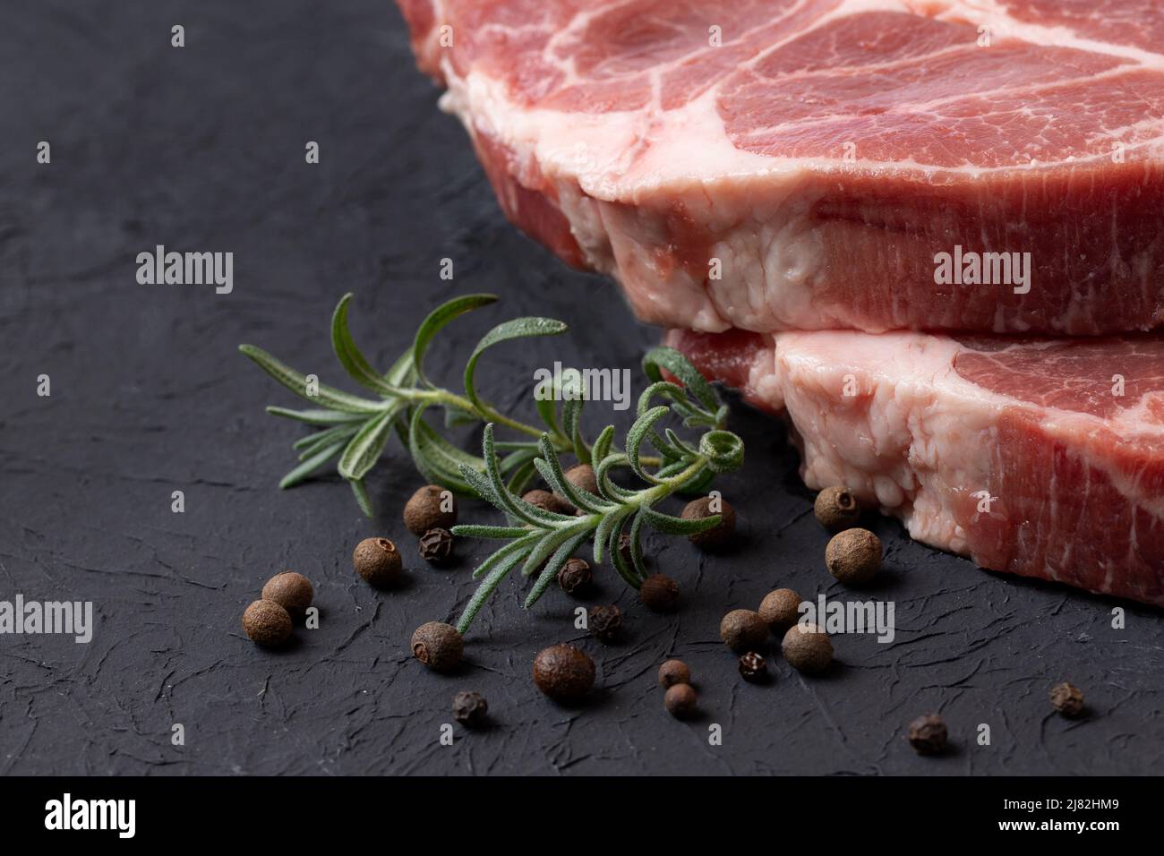 Steaks of raw marbled pork tenderloin on a black background with ...