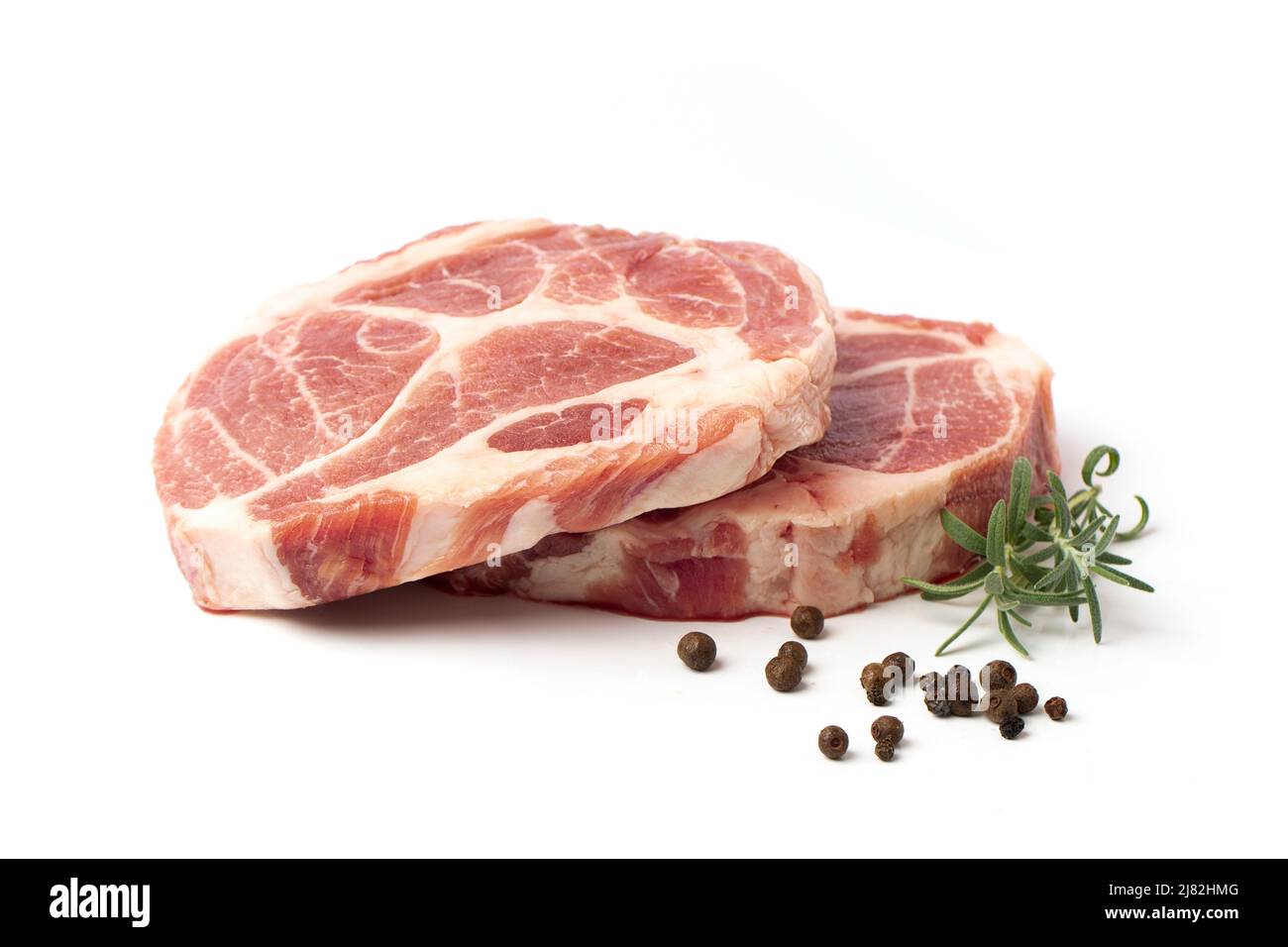 Steaks of raw marbled pork tenderloin with rosemary and peppercorns on ...