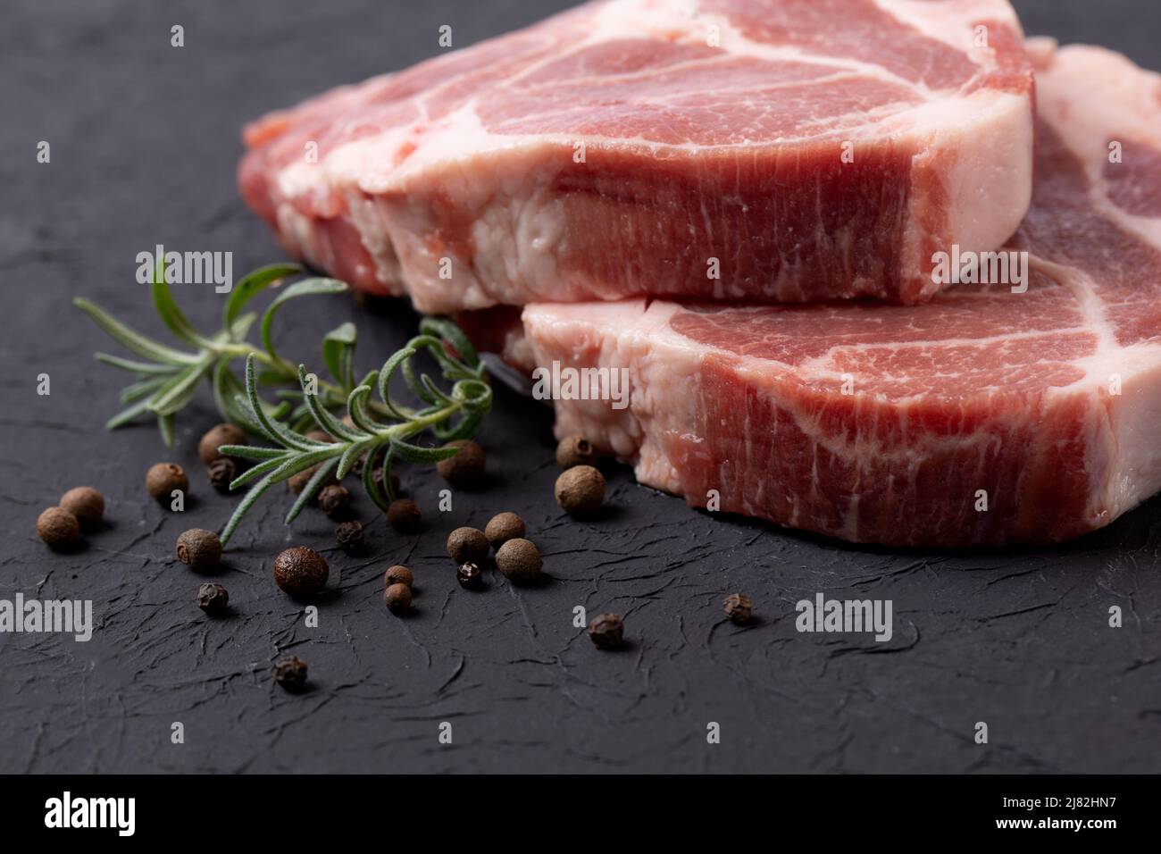 Steaks of raw marbled pork tenderloin on a black background with ...