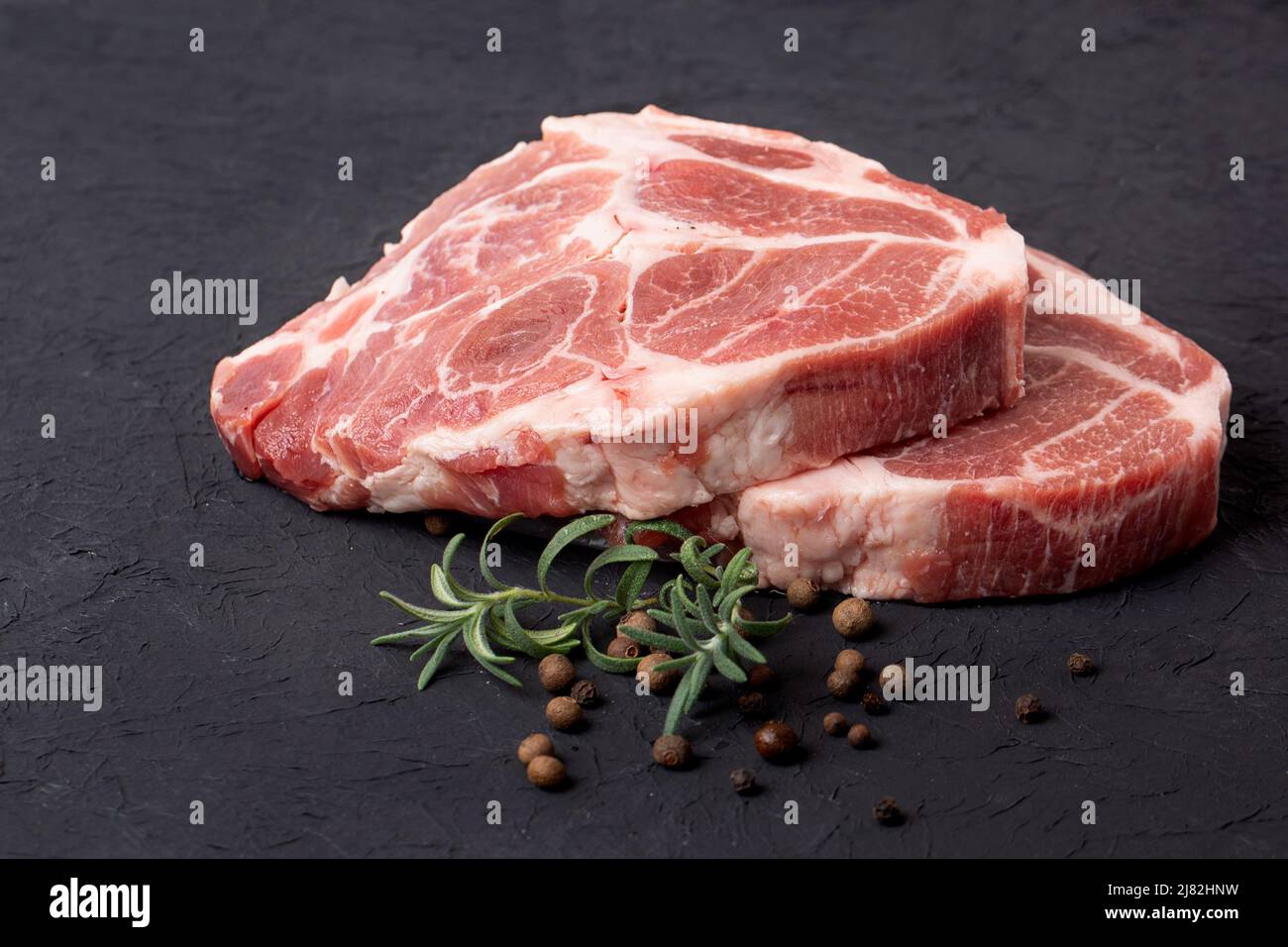 Steaks of raw marbled pork tenderloin on a black background with ...