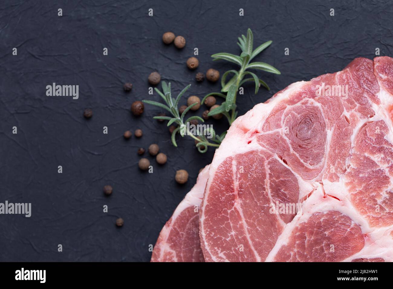 Steaks of raw marbled pork tenderloin on a black background with ...